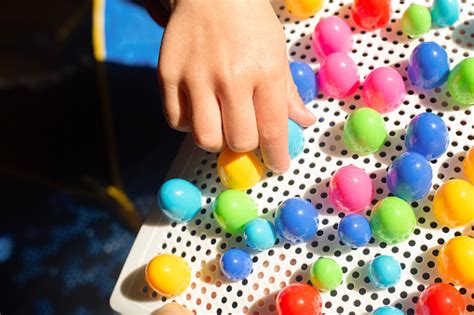 아기는 흰색 표면에 다채로운 모자이크를 가지고 놀고 있습니다 아이들은 창의력과 운동 능력을 개발하기 위해 밝은 생성자와 손을 잡습니다 조기 교육 미취학 아동을위한 퍼즐