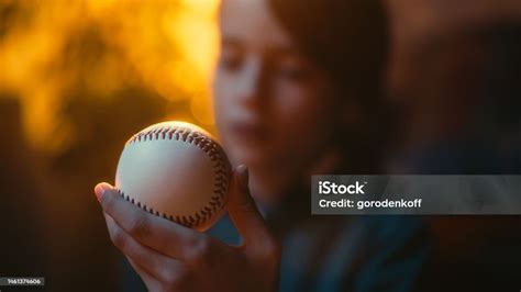 집에서 하얀 야구공을 들고 있는 젊은 스포츠 팬의 초상화를 클로즈업한다 흥분한 소년은 공을보고 둥글게 돌립니다 향수를 불러일으키는 복고풍 어린 시절의 개념으로 여가 시간을