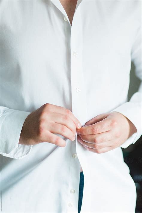man buttoning up his wedding shirt by stocksy contributor a model
