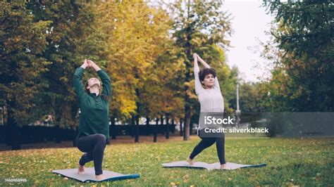 날씬한 여자 요가 학생 독수리 포즈 공원에서 강사와 함께 개별 연습 하는 동안 선생님의 지도 아래 학습 도구입니다 아름 다운가 자연 배경입니다 2명에 대한 스톡 사진 및
