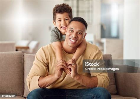 가족 사랑과 신뢰는 집 거실의 소파에 앉아 함께 유대감을 형성하는 아버지와 아들입니다 아이들 초상화 미소를 지으며 젊은 남자와 소년 아이가 휴식을 취하기 위해 집에 있다