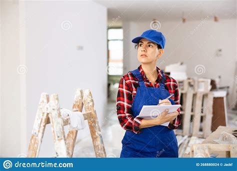 Skilled Woman Builder In Work Clothes Checking Project Documentation