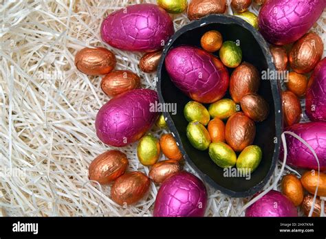 Pile Of Colorful Foil Wrapped Chocolate Easter Eggs In Pink Red Silver And Gold With Two