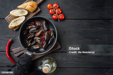 토마토 소스를 곁들인 맛있는 해산물 홍합 프라이밍 아이언 팬 블랙 우드 테이블 배경 상단 보기 플랫 레이 카피 스페이스 및
