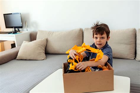 접힌 옷과 장난감으로 가득 찬 골판지 기부 상자를 들고있는 사랑스러운 소년 2022년에 대한 스톡 사진 및 기타 이미지 2022년 6 7 살 갈색 머리 Istock