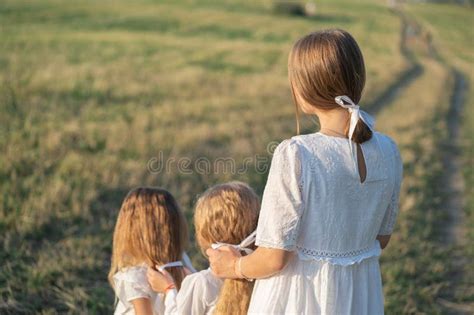 A Gentle Mother With Two Daughters In Nature Mom Braids Beautiful Hair For Her Daughters Stock