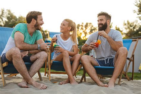 Group Of Friends Relaxing On A Beach While Drinking Cocktails Stock