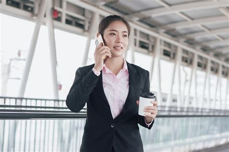 검은 양복을 입은 젊은 아시아 사업가가 폴더와 커피 한 잔을 들고 산책로 역에 서 있다 30 34세에 대한 스톡 사진 및 기타 이미지 30 34세 30 39세 개성