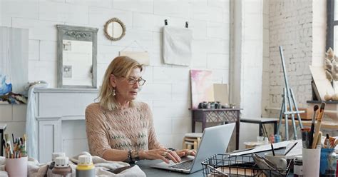 금발 머리를 가진 바쁜 여성 아티스트가 테이블에 앉아 자신의 스튜디오에서 노트북에 타이핑하고 있습니다 사진 Unsplash의 캐주얼 의류 이미지