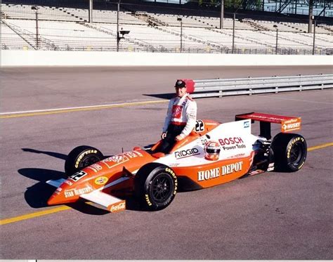 A Man Sitting On Top Of An Orange Race Car