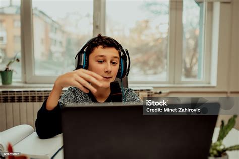 집에서 온라인 수업에 참석하는 소년 교사 및 학교 친구들과 연결하기 위해 노트북과 헤드셋을 사용하는 어린이 격리 중 학교 교육 및 사회적 거리 매스컴에 대한 스톡 사진 및