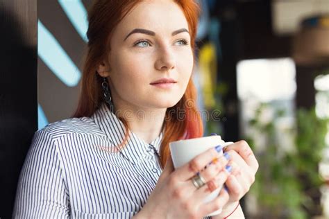 Молодая привлекательная женщина наслаждаясь чашкой кофе в кафе Стоковое Фото изображение