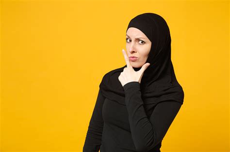 슬픈 화가 울고 혼란 스러운 젊은 아라비아 무슬림 여자 히 잡 블랙 의류 노란 벽 배경 스튜디오 초상화에 고립 포즈 사람들 종교적 이슬람 라이프 스타일 개념입니다 복사