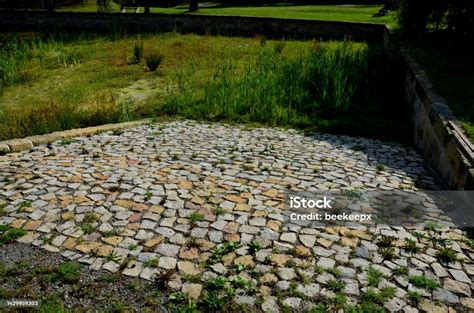 지형 아래에 묻혀있는 돌담이있는 연못 복원 경사 돌 포장 경사로가있는 화재 탱크 돌 블록은 박격포와 결합되었습니다 서식지는 물과 갈대의 성장입니다 건조한에 대한 스톡 사진