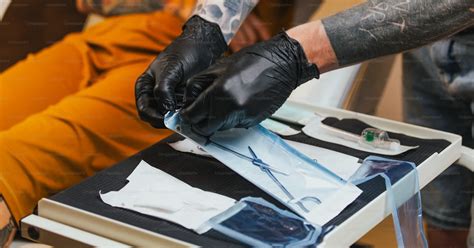 피어싱을 위해 멸균 장비를 여는 남자의 클로즈업 절차를 준비하는 피어싱 바디 피어싱 살롱 피어싱을 받는 여자 사진