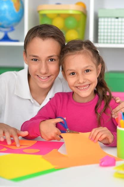Premium Photo Brother And Sister Sitting At Table And Spending Time Together