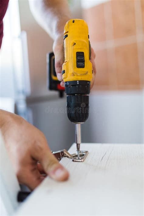 Close Up Of Man Assembling Furniture By Using Cordless Screwdriver