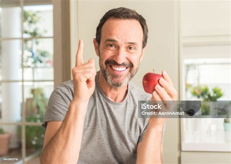 중 년 남자가 건강 한 빨간 사과 먹는 행복 한 얼굴 넘버 원 아이디어 또는 질문 가리키는 손가락 놀 가리키기에 대한 스톡 사진 및 기타 이미지 Istock