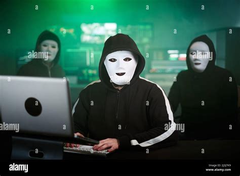 masked hacker is using computer for organizing massive data breach