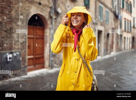 A Young Girl In A Yellow Raincoat Walks On The Street In A Peaceful