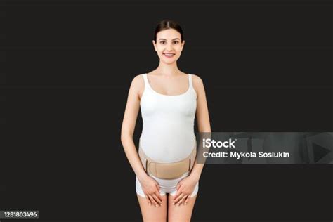 검은 배경에 탄성 출산 밴드를 입고 임신 한 여성의 초상화와 복사 공간 정형 외과 복부 지원 벨트 개념 25 29세에 대한 스톡