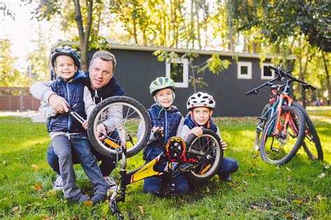 아버지의 날에는 친절 한 가족의 아버지와 3 명의 아들과 공동 활동적인 휴식을 외부에 아빠는 아들에 게 자전거를 수리 하 라고 가르칩니다 아이는 공원에서 화창한 날에 공기