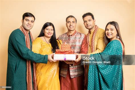 베이지색 배경에 고립된 빨간 선물 상자를 들고 전통 천을 입은 행복한 인도 가족 디왈리 축제를 축하합니다 25 29세에 대한 스톡 사진 및 기타 이미지 Istock