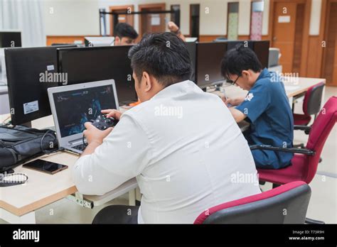 Back Of Asian University Student Playing Game In The Classroom During Back Of Asian University Student Playing Game In The Classroom During