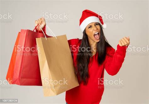 젊은 여자 종이 쇼핑백 빨간색과 산타 클로스 모자와 함께 크리스마스에 대 한 준비가 회색 배경 크리스마스 쇼핑 선물 축 하
