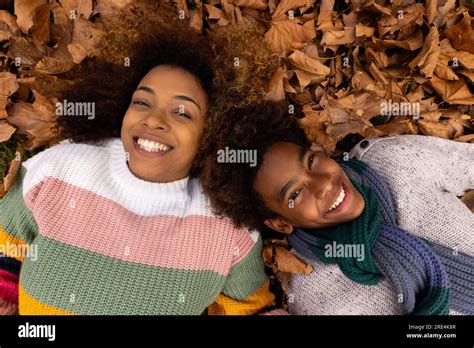 Portrait Of Happy African American Mother And Son Lying In Pile Of Leaves In Garden Stock Photo