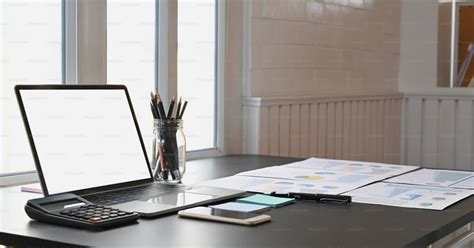 현대적인 업무용 책상 위에 놓인 비즈니스 장비액세서리 사진 평평한 흰색 빈 화면 노트북 스마트 폰 계산기 연필 홀더 포스트잇 및 그래픽 차트가 검은 테이블에 놓여