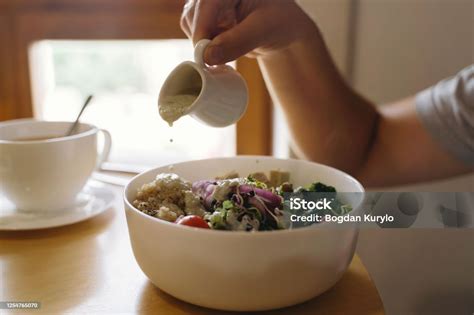 부처님 그릇 건강한 식습관 레스토랑에서 비건 식사에 소스를 붓는 남자 아보카도 무 브로콜리 두부 토마토 쿠스쿠스 마이크로 그린 및 참깨와 그릇 부다 보울에 대한 스톡 사진