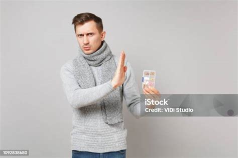 회색 스웨터에 우려 젊은 남자 스카프 매일 알 약 상자 회색 배경에 고립 손바닥 표시 중지 제스처 건강 아픈 아픈 질병 치료 추운 계절 개념 복사 공간을 비웃는 다 가을에