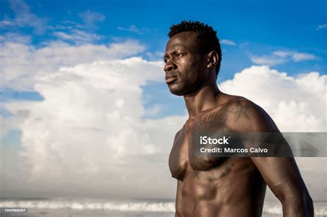 머리와 어깨를 닫습니다 젊은 매력적이 고 적합 흑인 아프리카계 미국인 남자 강한 근육 질의 몸 포즈 시원한 모델 태도 해변에 고립 된 여름 푸른 하늘 남자에 대한 스톡 사진