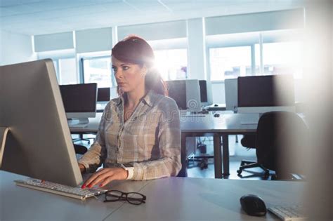 Female Professional Using Keyboard And Mouse At Desk In Computer Lab With Monitor And Eyeglasses