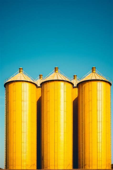 Three Large Yellow Silos Sitting Next To Each Other On Field