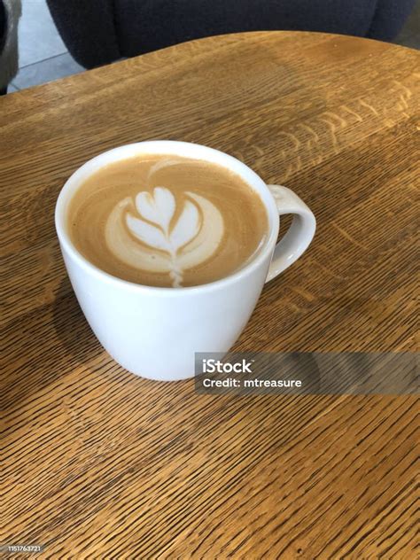 나무 테이블에 화이트 커피 라 떼 아트의 이미지 손잡이와 화이트 컵 찻잔 카푸치노 거품 아트 디자인 장미 꽃과 커피 숍 카페 실내 다과 잎에서 커피 휴식을 취하고 비오는 날