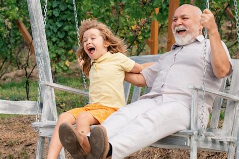 Premium Photo Young Grandson And Old Grandfather Swinging In Spring