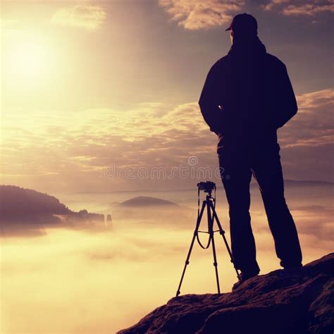 Photographer With Folden Tripod On End Of Cliff Thinking Misty