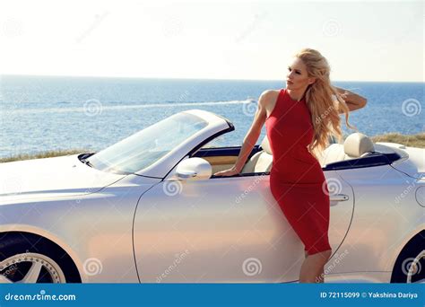 Mujer Con El Pelo Rubio En El Vestido Rojo Que Presenta Al Lado Del