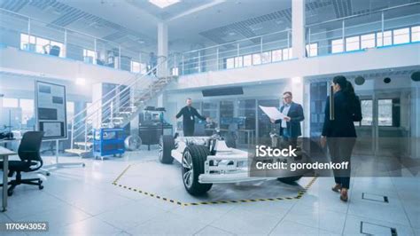 전기 자동차 섀시 프로토타입을 작업하는 동안 자동차 설계 엔지니어가 이야기하고 있습니다 혁신 실험실 시설 개념 차량 프레임에는