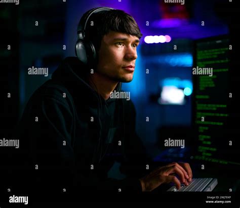 Low Key Lighting Shot Of Male Computer Hacker Sitting In Front Of Screens Breaching Cyber