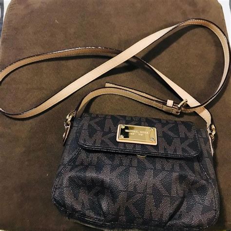 A Brown And Black Purse Sitting On Top Of A Bed Next To A Handbag