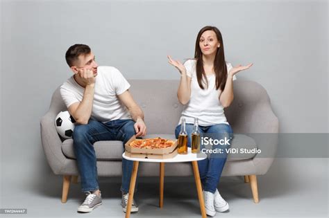 흰색 T 셔츠에 무관심 커플 여자 지루한 남자 축구 팬 응원 좋아하는 팀 회색 배경에 고립 된 손을 확산 지원 사람들의 감정 스포츠 가족 레저 라이프 스타일 개념입니다 T