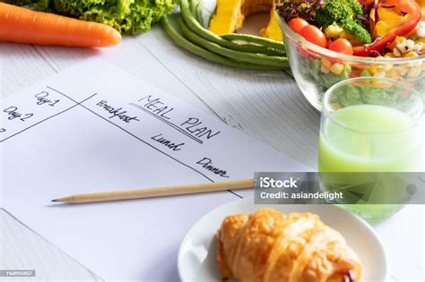 칼로리 제어 식사 계획 음식 다이어트와 체중 감소 개념 샐러드 과일 주스 빵 야채와 종이에 식사 계획 테이블의 상단보기 수첩에
