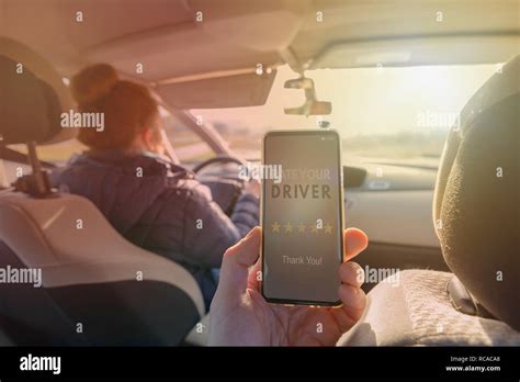 Passenger Is Sitting On The Back Seat Of The Car And Using Smart Phone App To Rate A Driver