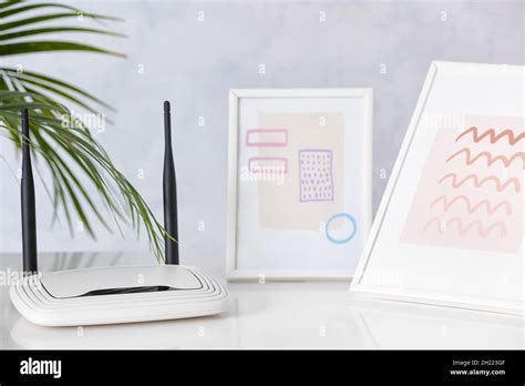 Modern Wi Fi Router And Pictures On Table Near White Wall Stock Photo Alamy