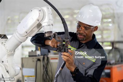 아프리카계 미국인 남성 엔지니어 작업자가 공장에서 자동 로봇 암 기계를 유지 보수합니다 스마트 팩토리에서 드라이버가 있는 검은 남성 기술자 점검 수리 자동 로봇 핸드 머신