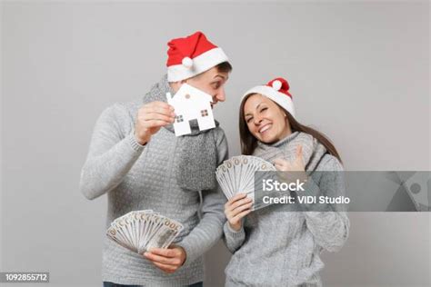 빨간색 산타 크리스마스 모자 회색 스웨터 스카프에 커플 여자 남자 회색 벽 배경 스튜디오 초상화에 고립 된 돈을 잡아 행복 한 새 해 2019 축 하 휴일 파티 개념입니다