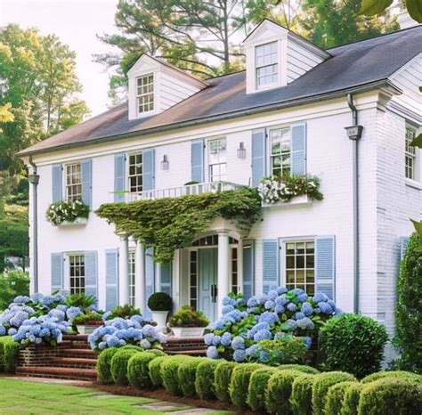 Classic White House With Blue Shutters And Beautiful Flower Garden